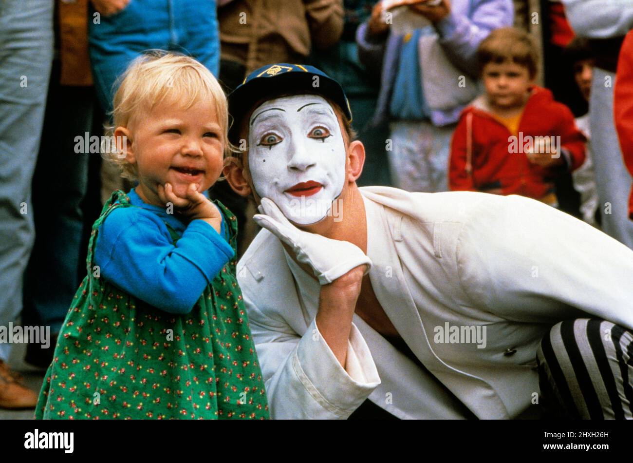 Mime performing at street fair mimicing a little girls expressions and ...
