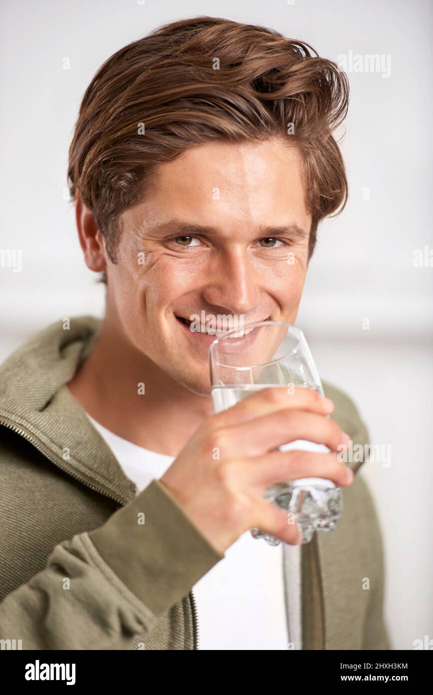 Keeping hydrated. A young man drinking a glass of water Stock Photo - Alamy
