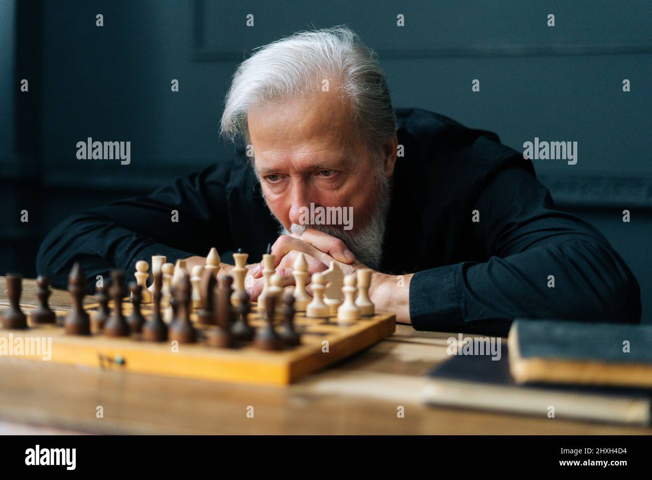 Close-up of pensive gray-haired senior older man thinking game strategy ...