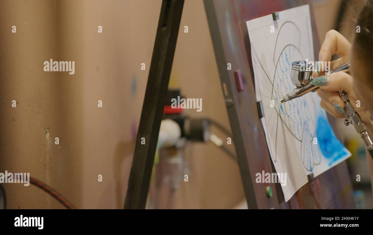 Woman artist learns to paint with airbrush with acrylic dye, paper and ...