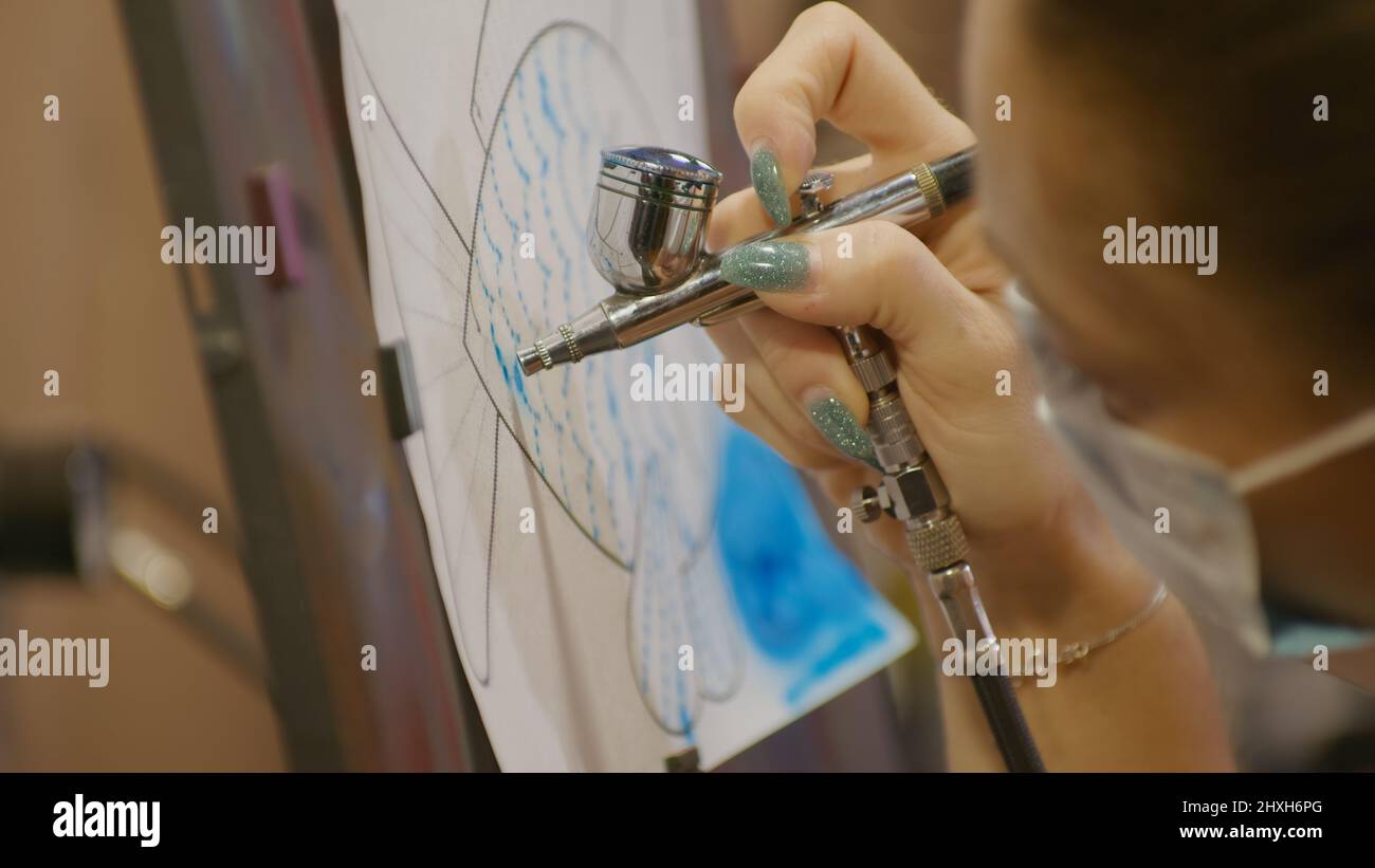 Woman artist learns to paint with airbrush with acrylic dye, paper and ...