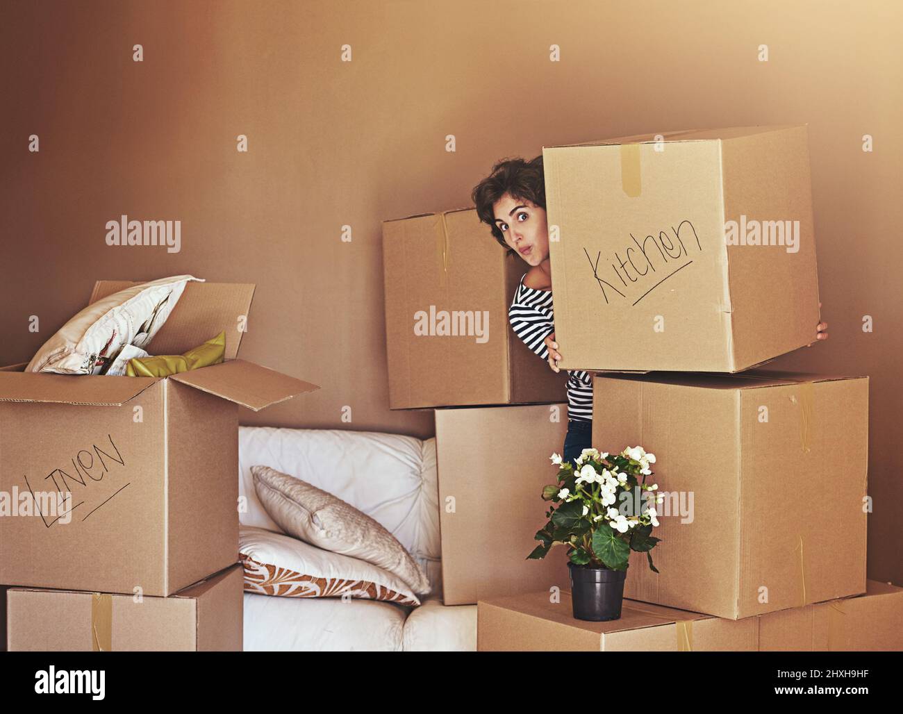Packing shenanigans. Shot of a playful young woman packing up on moving ...
