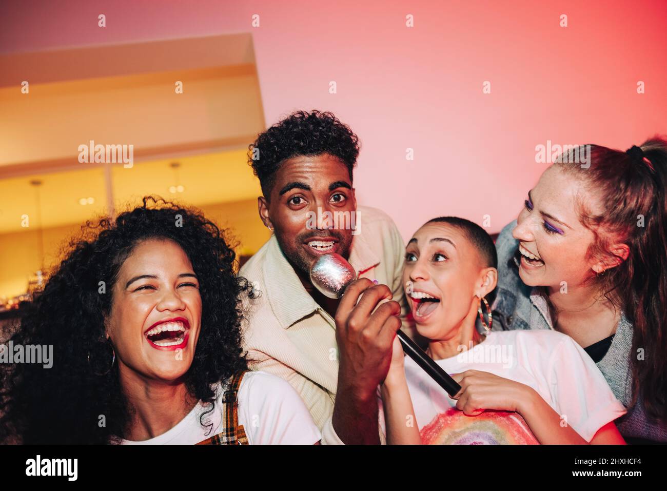 Happy friends singing their favourite song on karaoke night. Cheerful ...