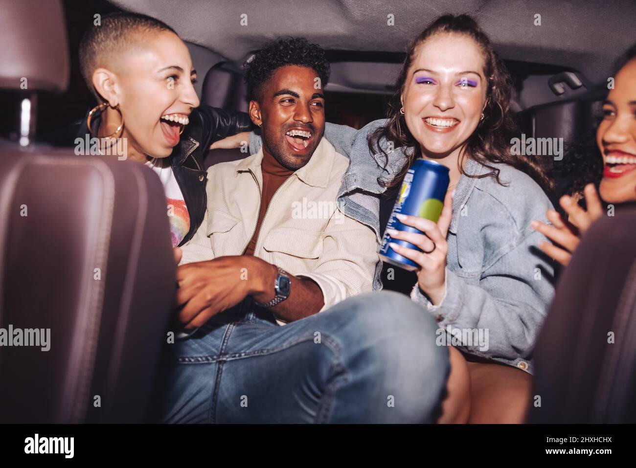 Fun in the back seat. Group of four happy friends laughing together ...
