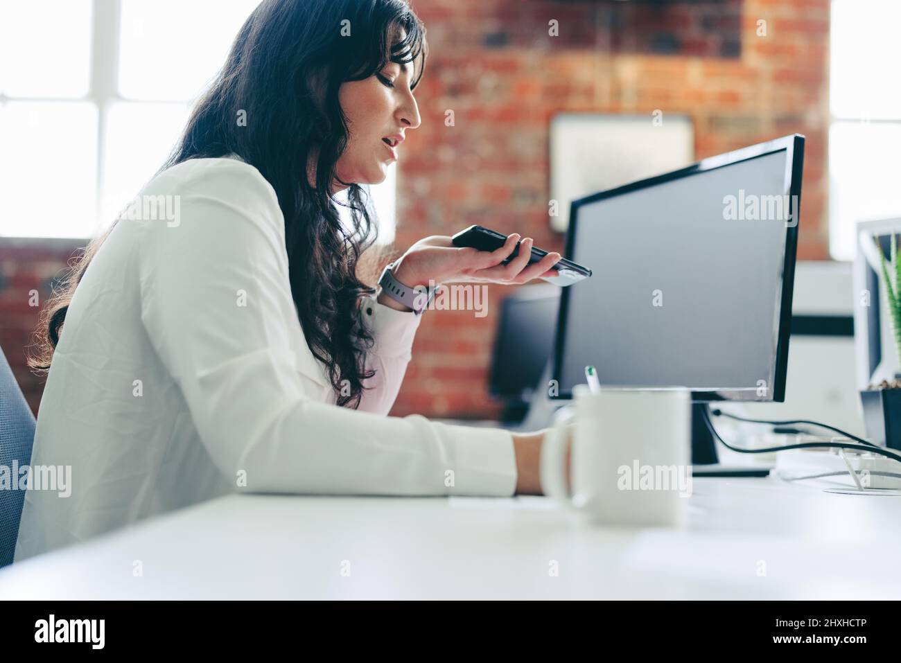 Contacting business clients in the office. Focused young businesswoman ...