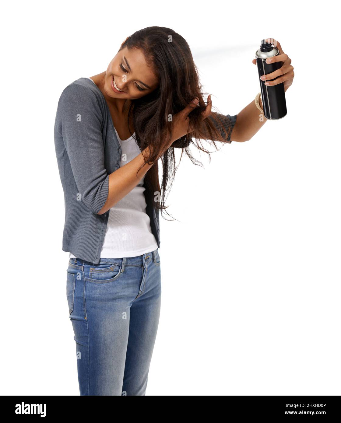 Im my own stylist. A young ethnic woman using hairspray on her hair ...