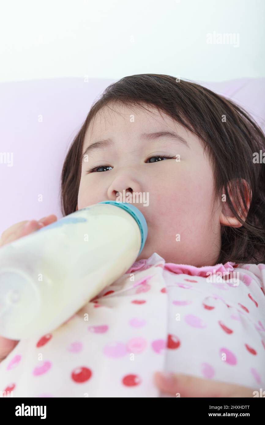Closeup Cute Asian Girl Sucking Up Milk Bottle In Bed Drinking Milk