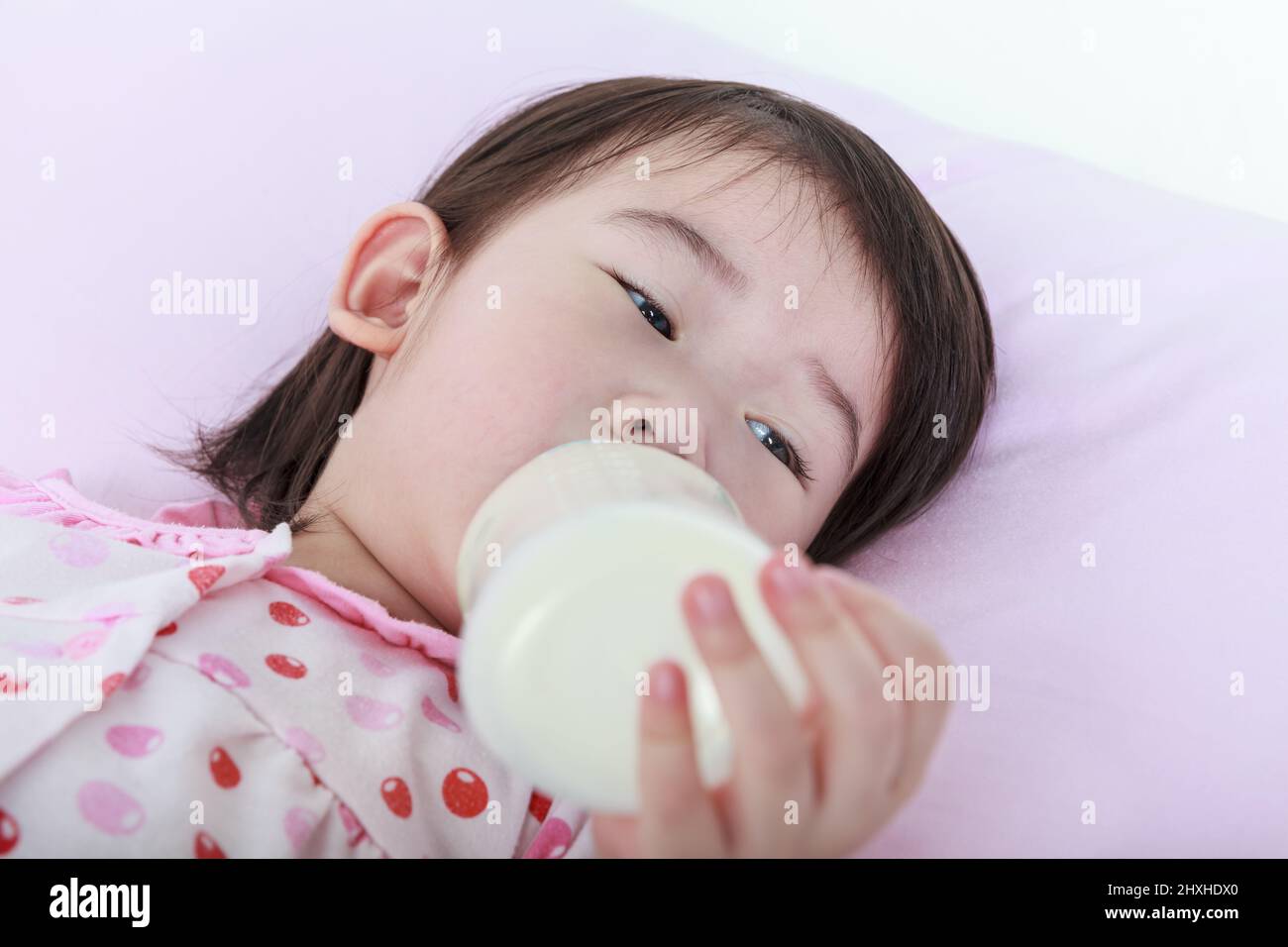 Closeup Cute Asian Girl Sucking Up Milk Bottle In Bed Drinking Milk