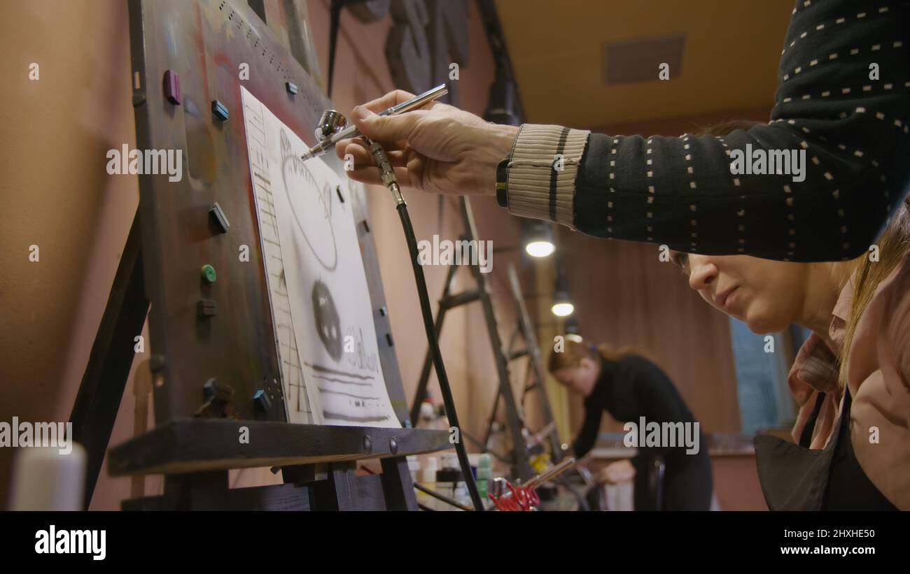 Woman artist learns to paint with airbrush with acrylic dye, paper and ...