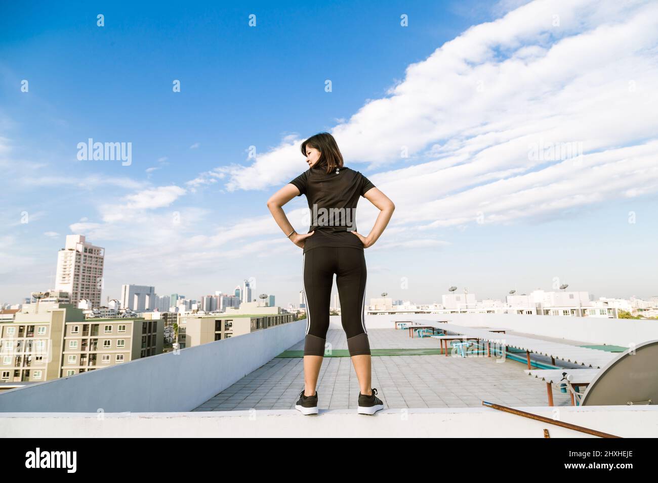 Sport asian woman stretching exercise on top of building blue sky cloud ...
