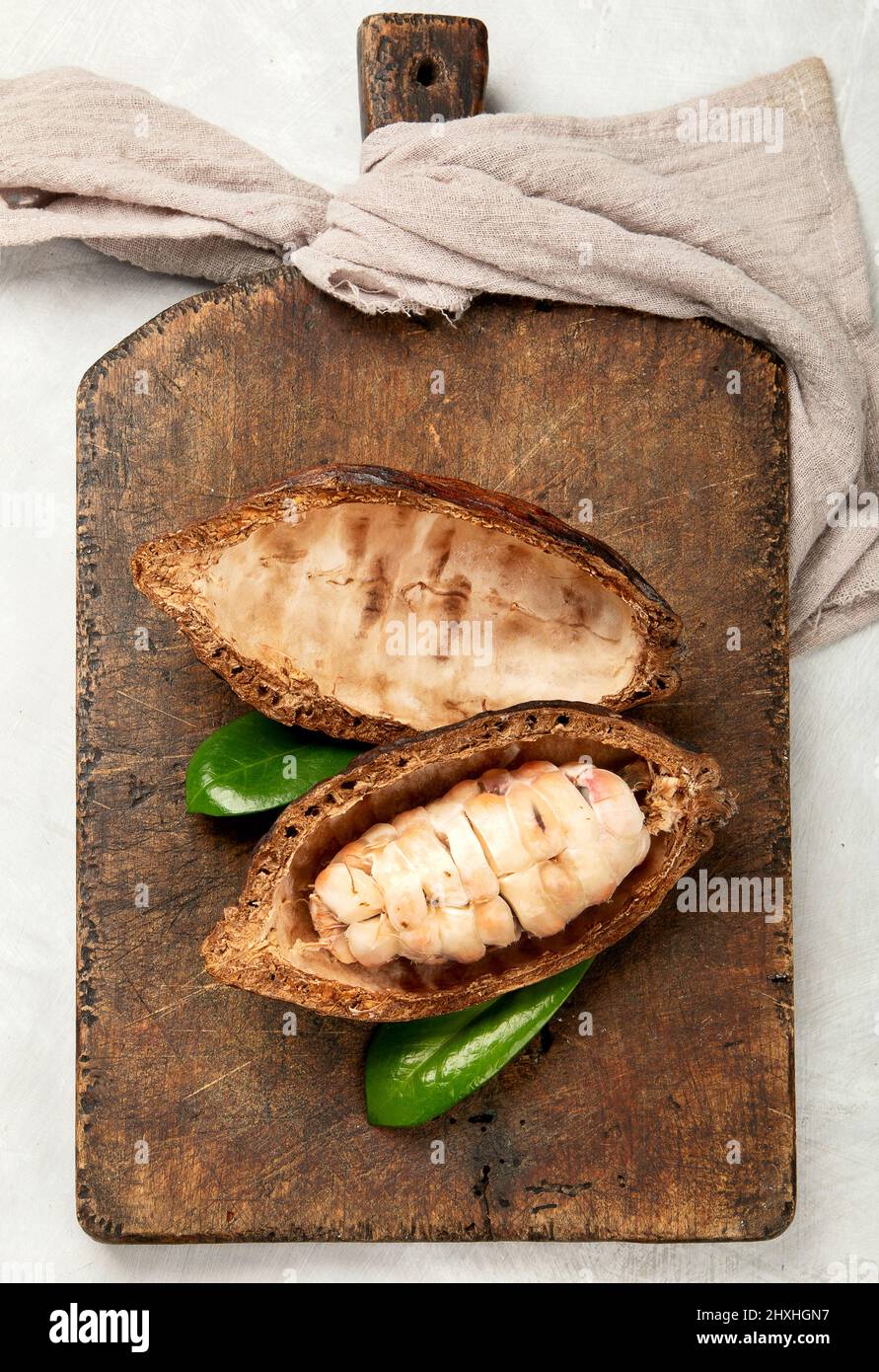 Fresh cocoa pod cut exposing cocoa seeds on white background, top view ...