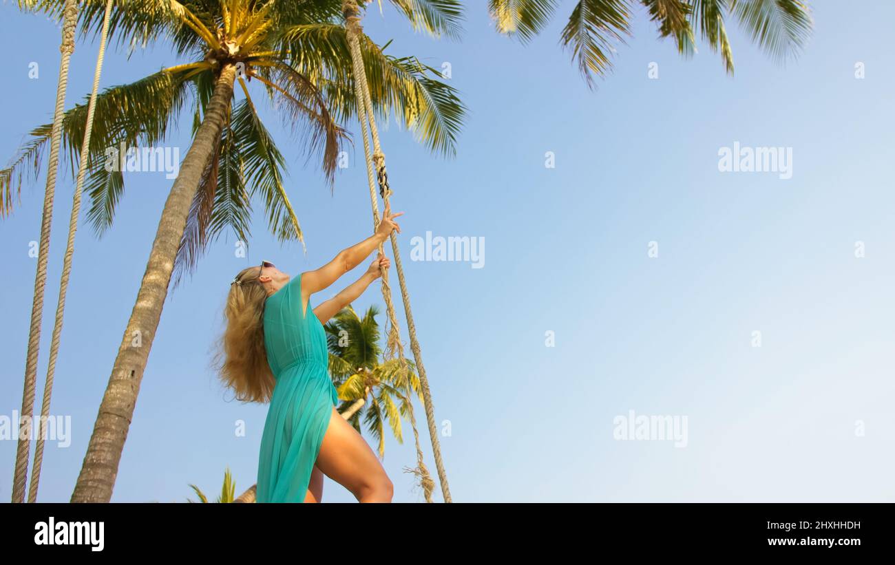 Seductive woman swinging on a swing on a tropical beach, on shores of the turquoise sea. Concept ...