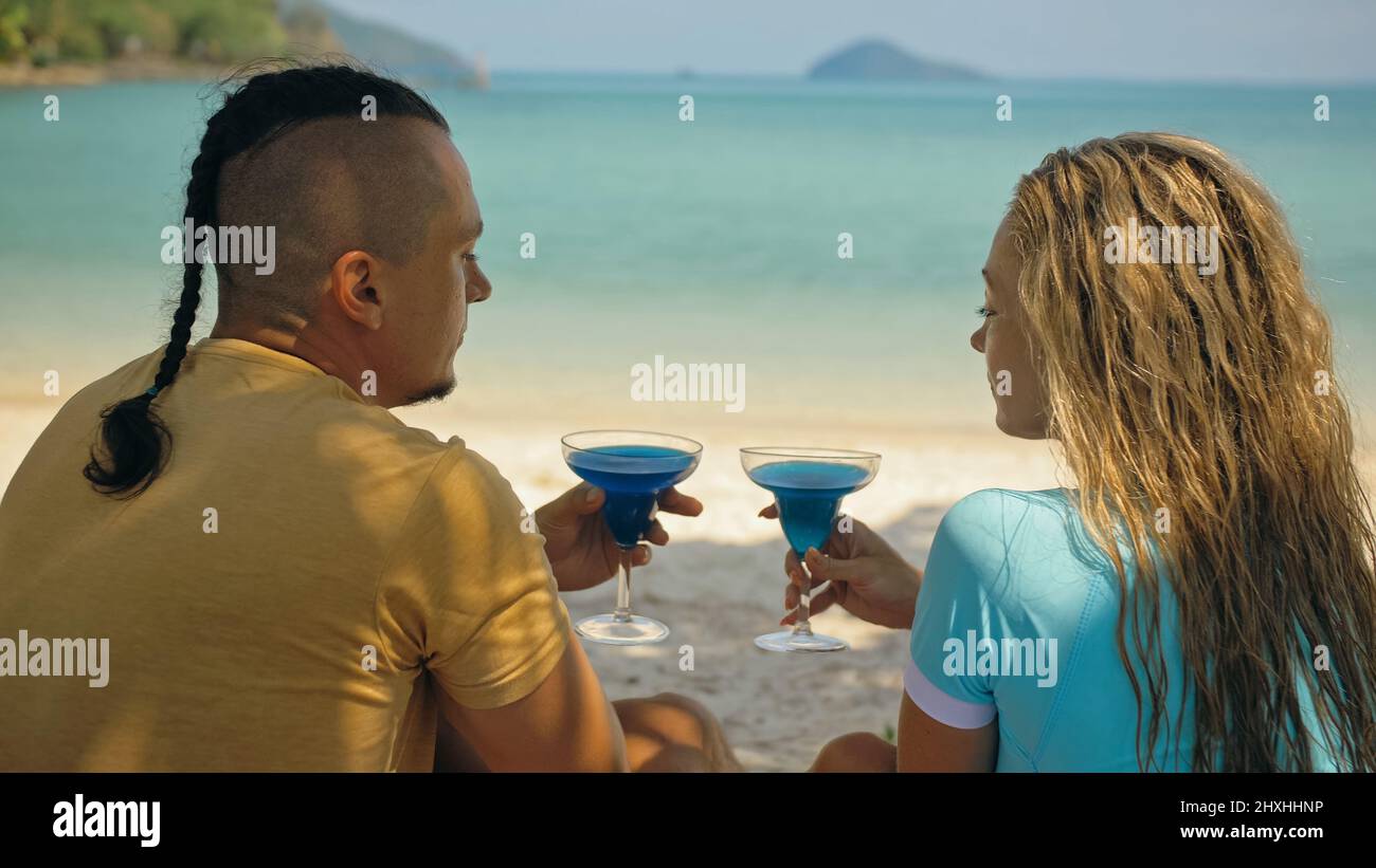 The love couple is holding a glass of blue curacao cocktail, on sea ...