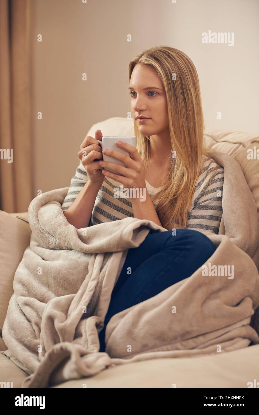 Relaxing with a cup of java. Shot of an attractive young woman drinking ...
