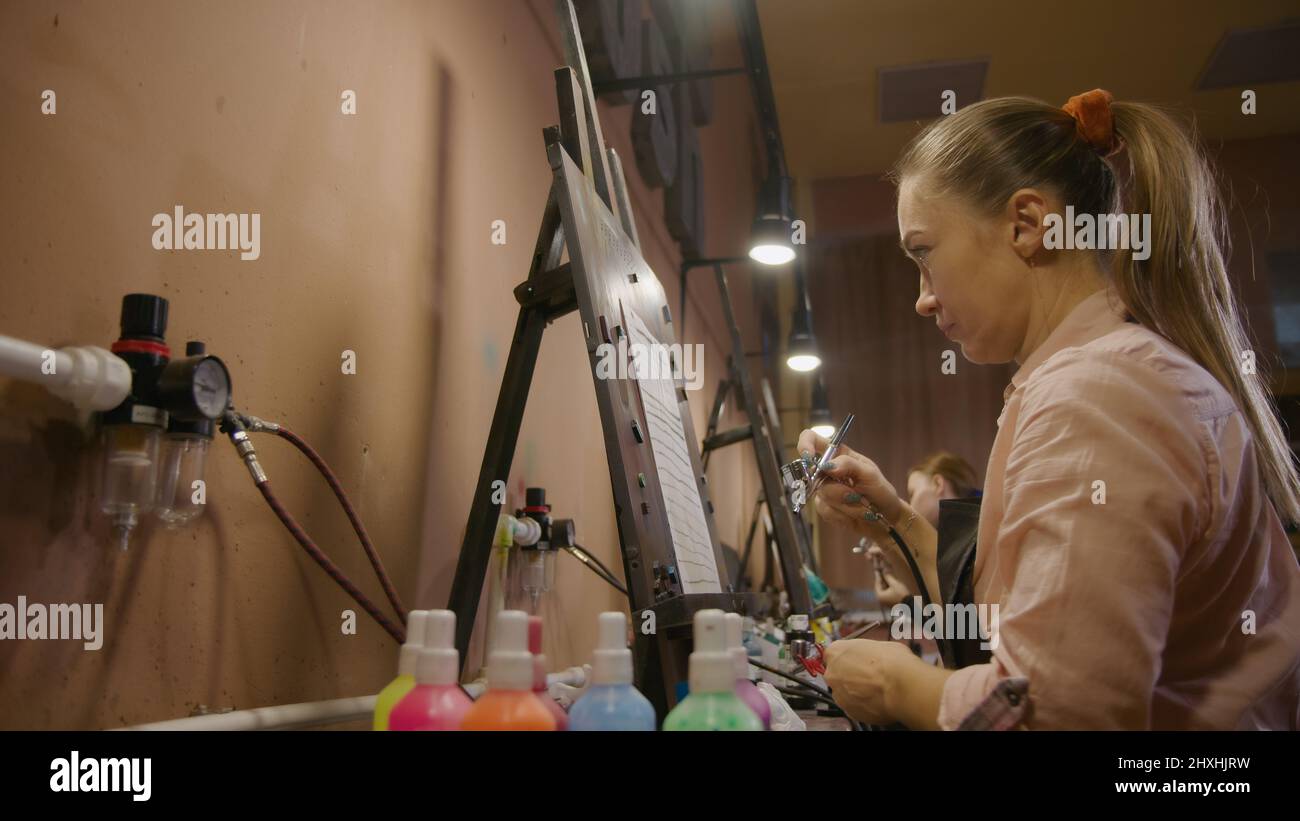 Woman artist learns to paint with airbrush with acrylic dye, paper and ...