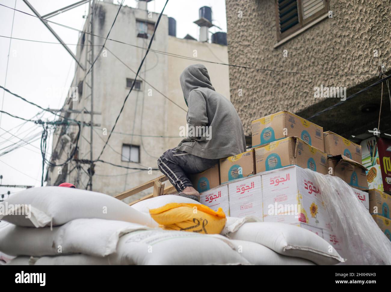 A Palestinian worker sitting on boxes from a wheat mill, in the ...