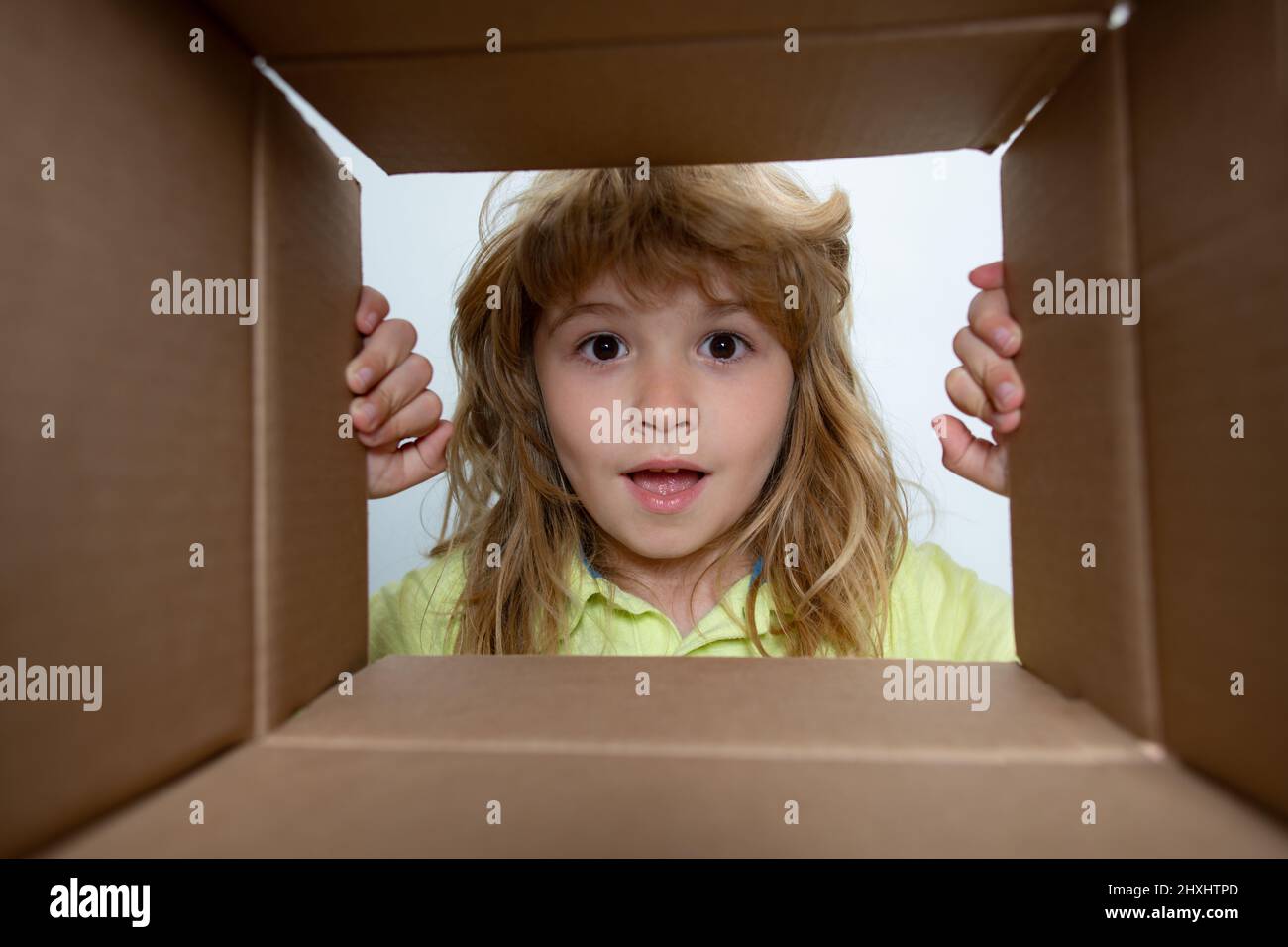 Surprised child boy age 7 year unpacking, opening carton box and ...