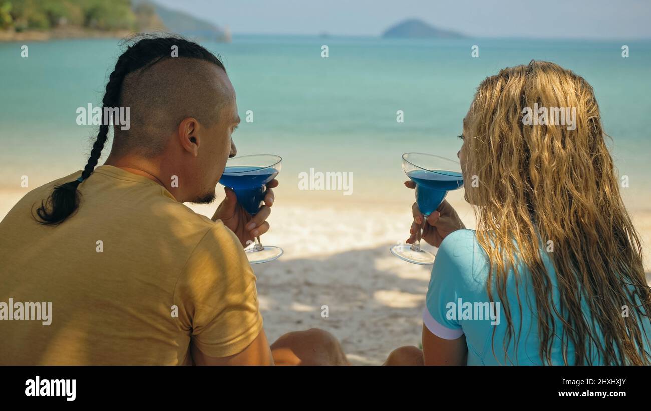 The love couple is holding a glass of blue curacao cocktail, on sea ...