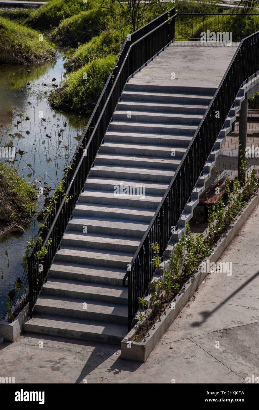 Concrete staircase and floor with iron railing lead up from footpath ...