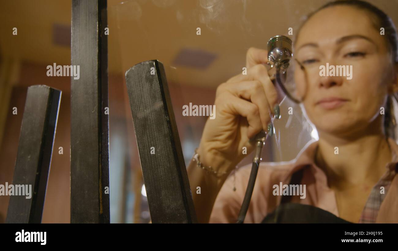 Woman artist learns to paint with airbrush with acrylic dye, paper and ...