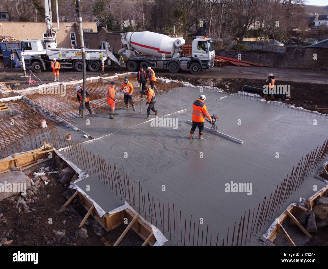 Workmen onsite at house construction, pouring base concrete layer from ...