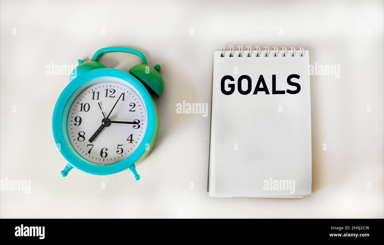 Notepad with the words Goal on the table with a clock. Motivation ...