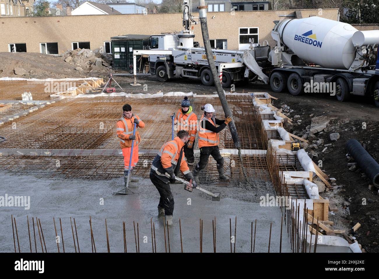 Workmen onsite at house construction, pouring base concrete layer from ...
