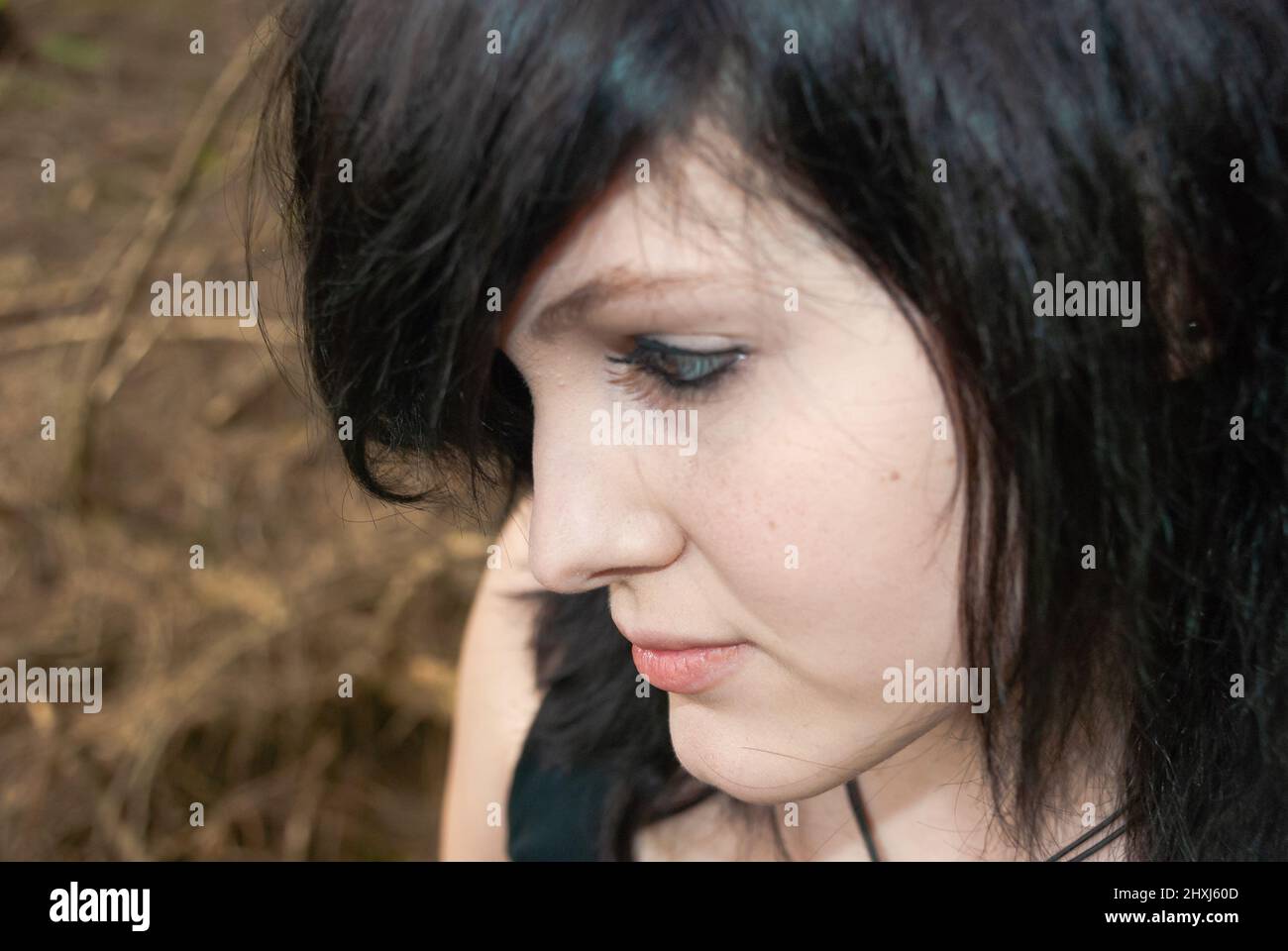 Punk emo girl, young adult with black hair and eyeliner, looking away ...