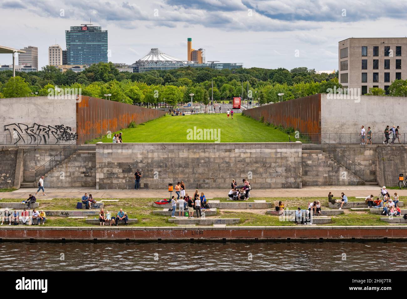 The Spreebogenpark in Berlin, Germany, park in the city center with people relaxing at river ...