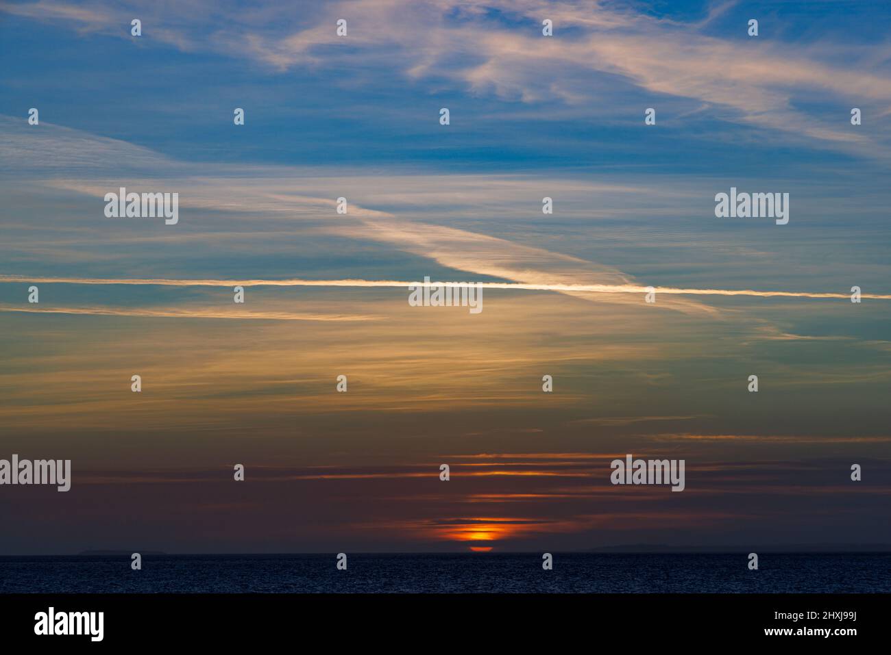 The sun disappearing behind some cloud cover and lighting up the clouds ...