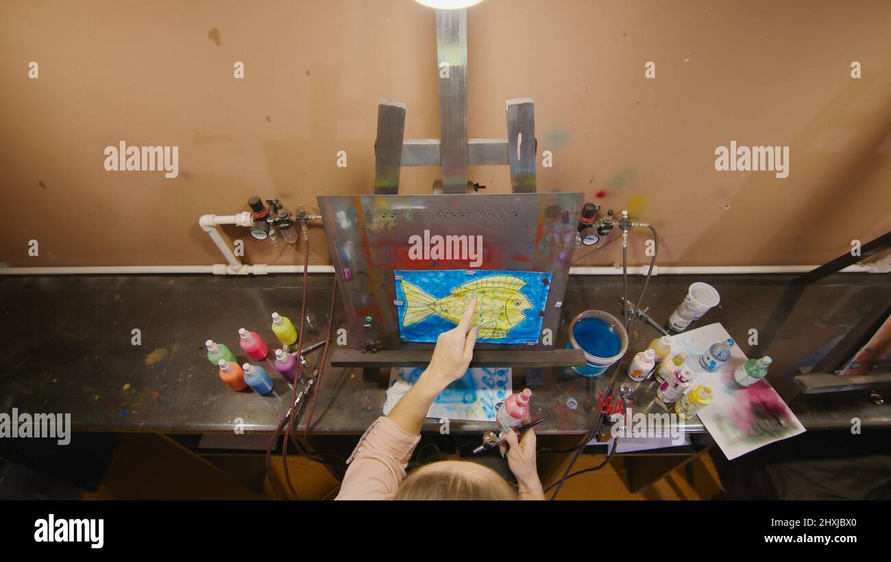 Woman artist learns to paint with airbrush with acrylic dye, paper and ...
