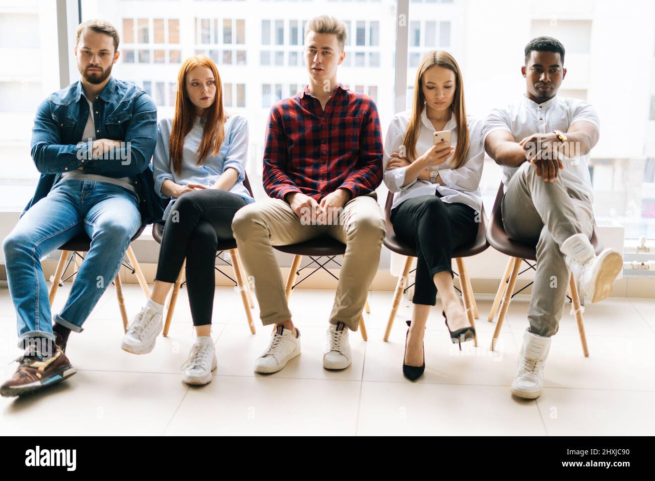 Front view of bored young diverse multi-ethnic job candidates in casual ...