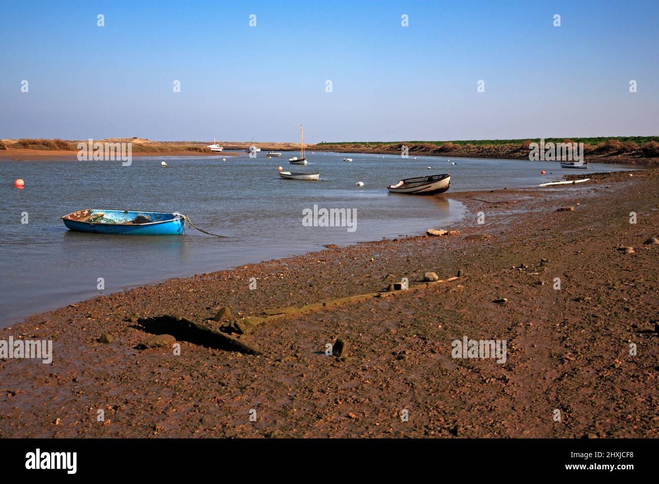 Boats in creek at ebb tide in salt marshes on the North Norfolk coast ...