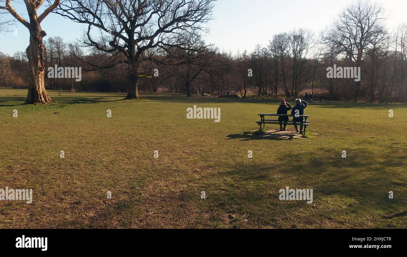 A couple take a bench seat in the late February sunshine on the ...