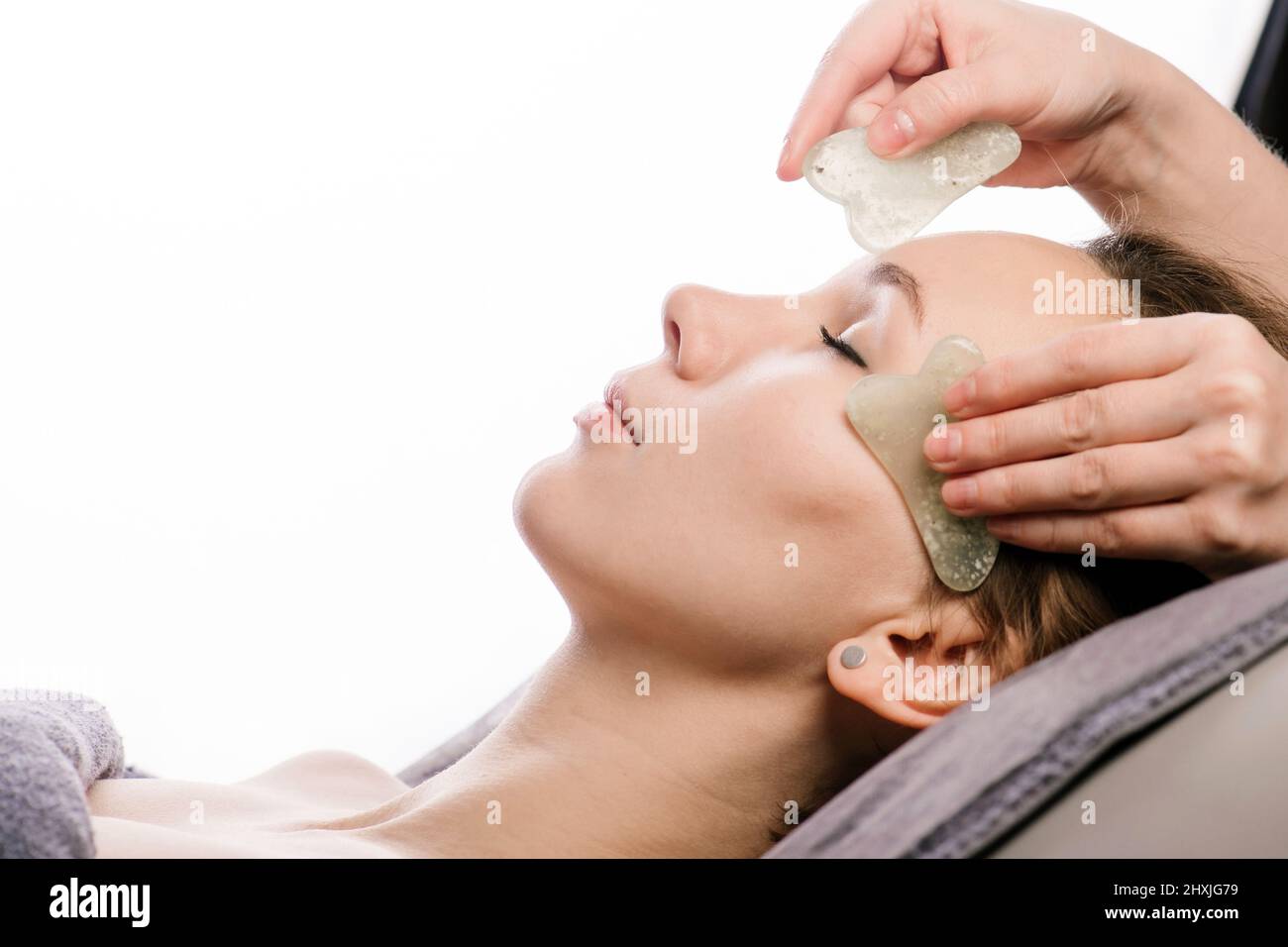 Gua sha massage of a woman in a beauty salon over white background Stock Photo - Alamy