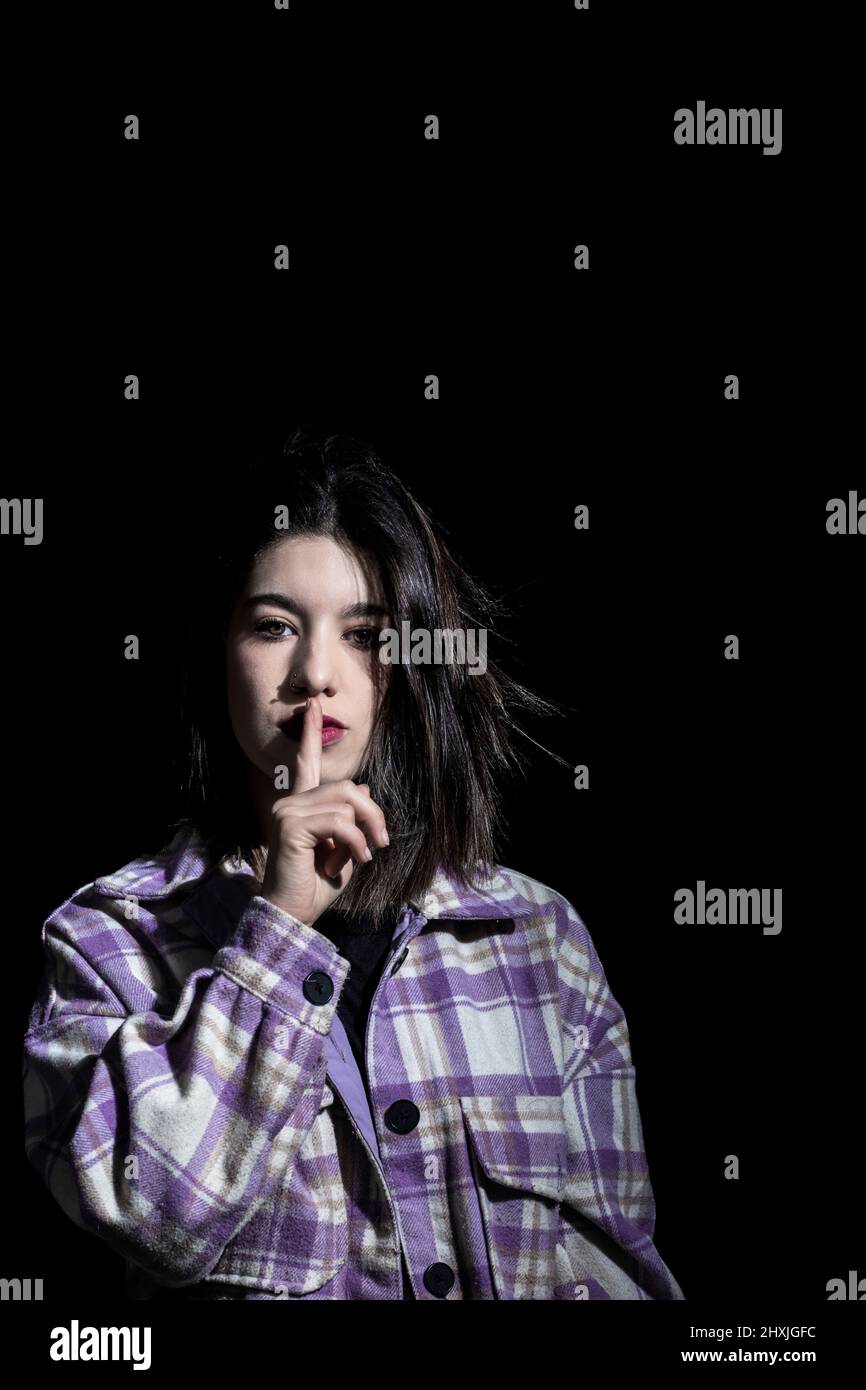 brunette woman commanding silence on black background Stock Photo - Alamy