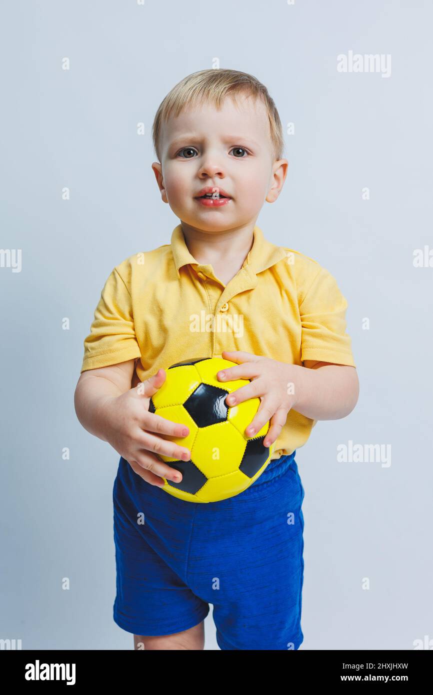A little boy with a soccer ball in his hands on a white background, a ...