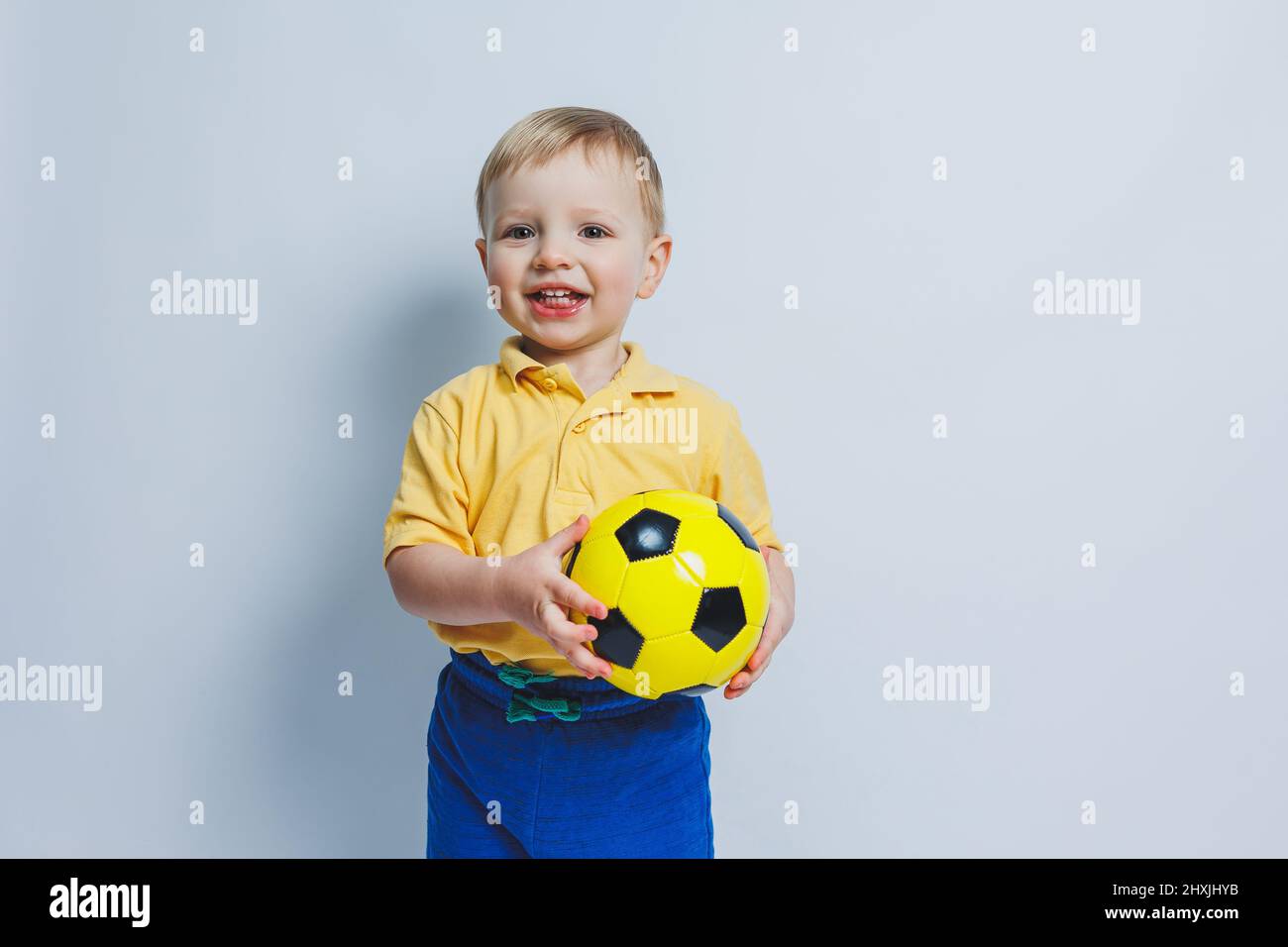 A little boy with a soccer ball in his hands on a white background, a ...