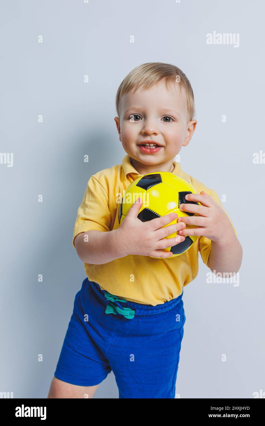 A little boy with a soccer ball in his hands on a white background, a ...