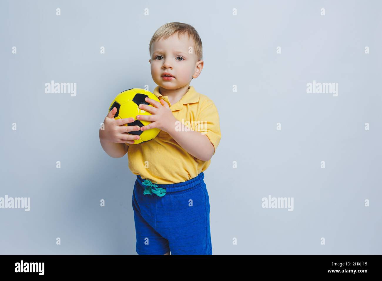 A little boy with a soccer ball in his hands on a white background, a ...