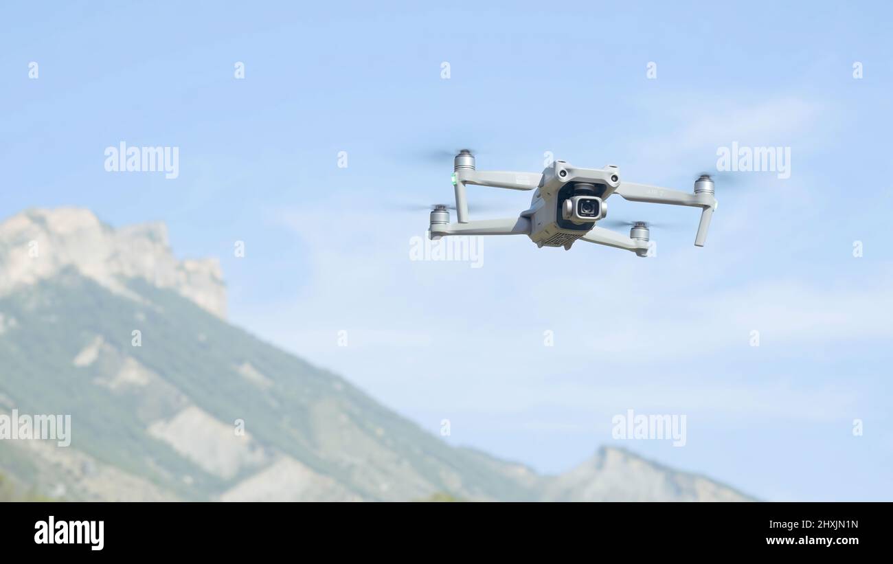 Aerial view of a quadcopter flying above green mountains on morning ...