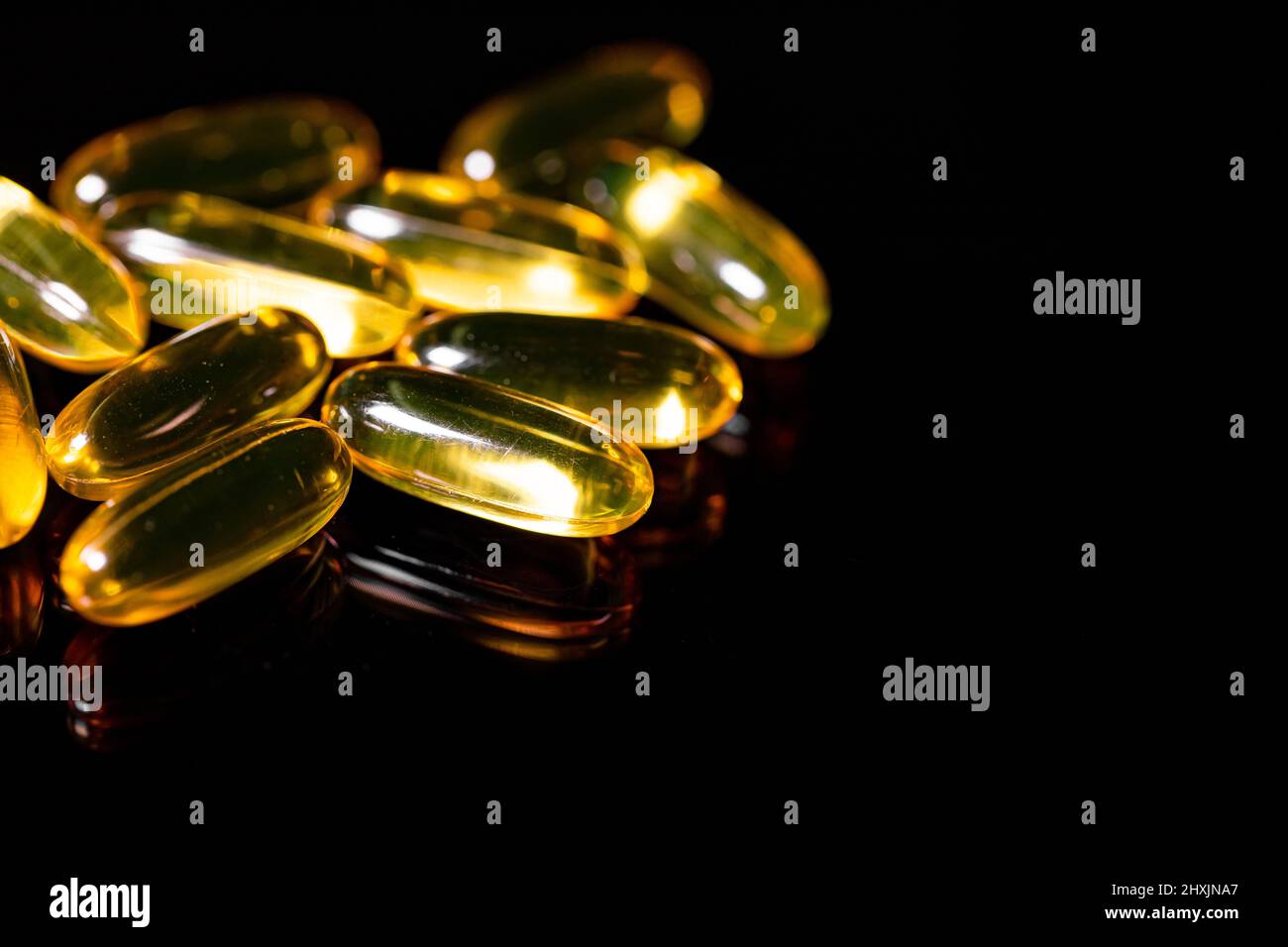 Macro Close up of Omega 3 gel capsule on a reflective black background ...