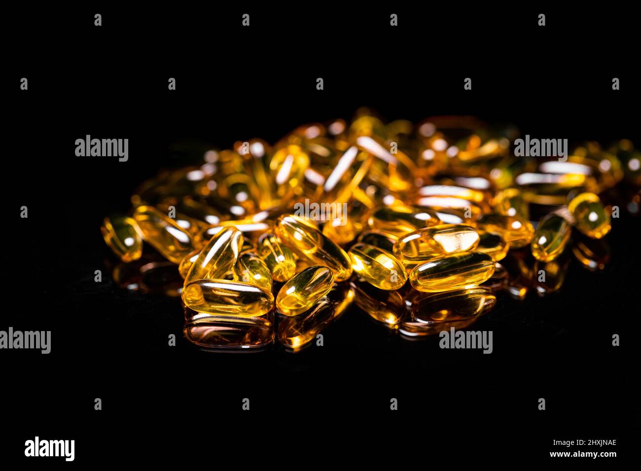 Macro Close up of Omega 3 gel capsule on a reflective black background ...