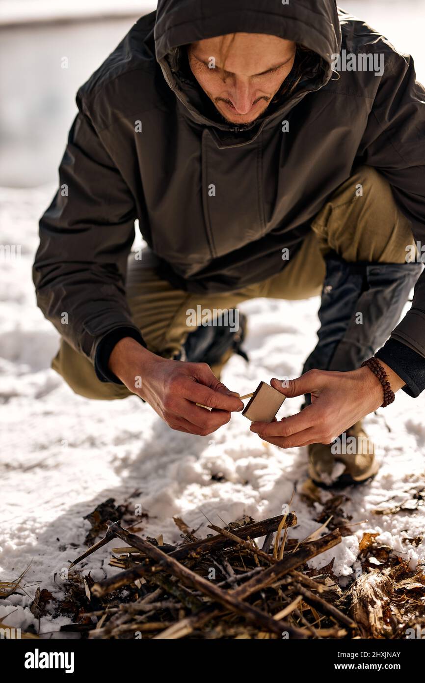 focused Man starts a fire in forest. Lighting a fire in nature, forest ...