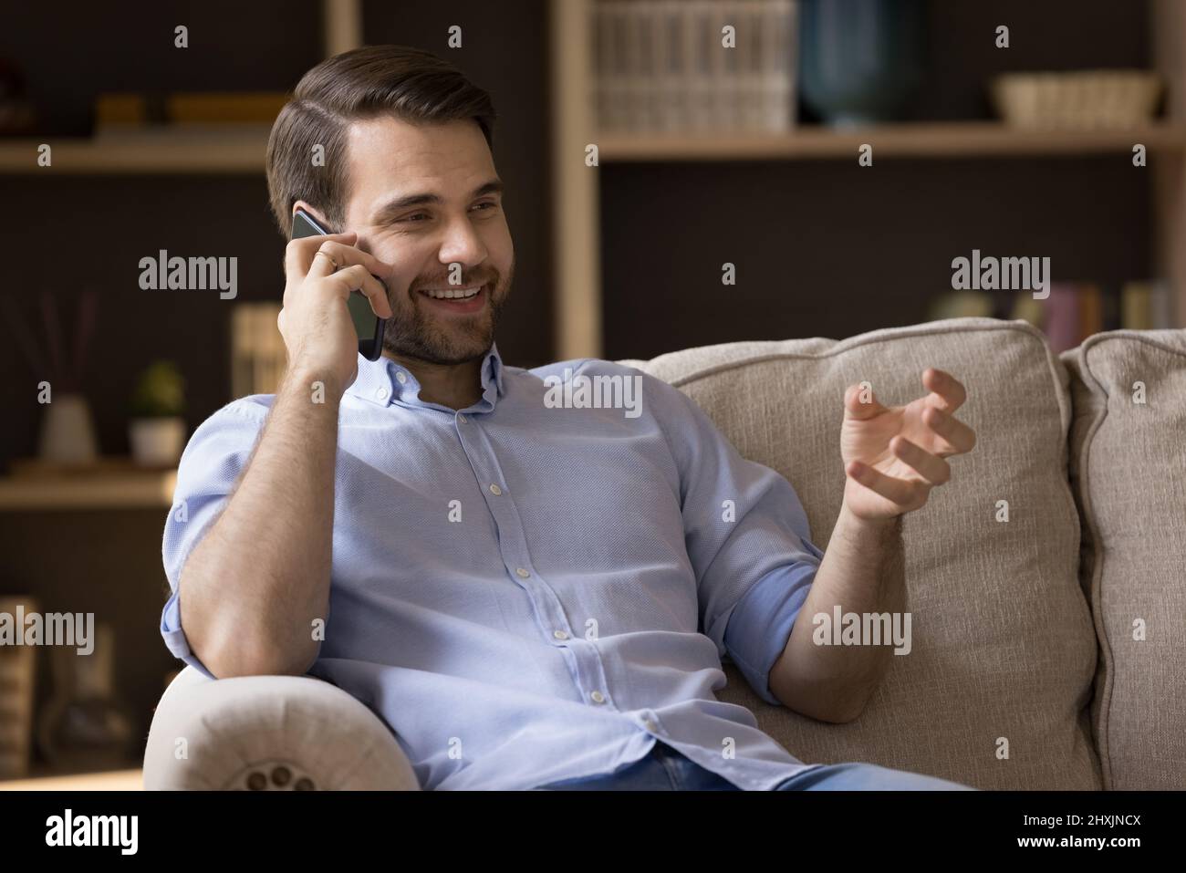 Relaxed millennial guy sitting on sofa having nice telephone ...