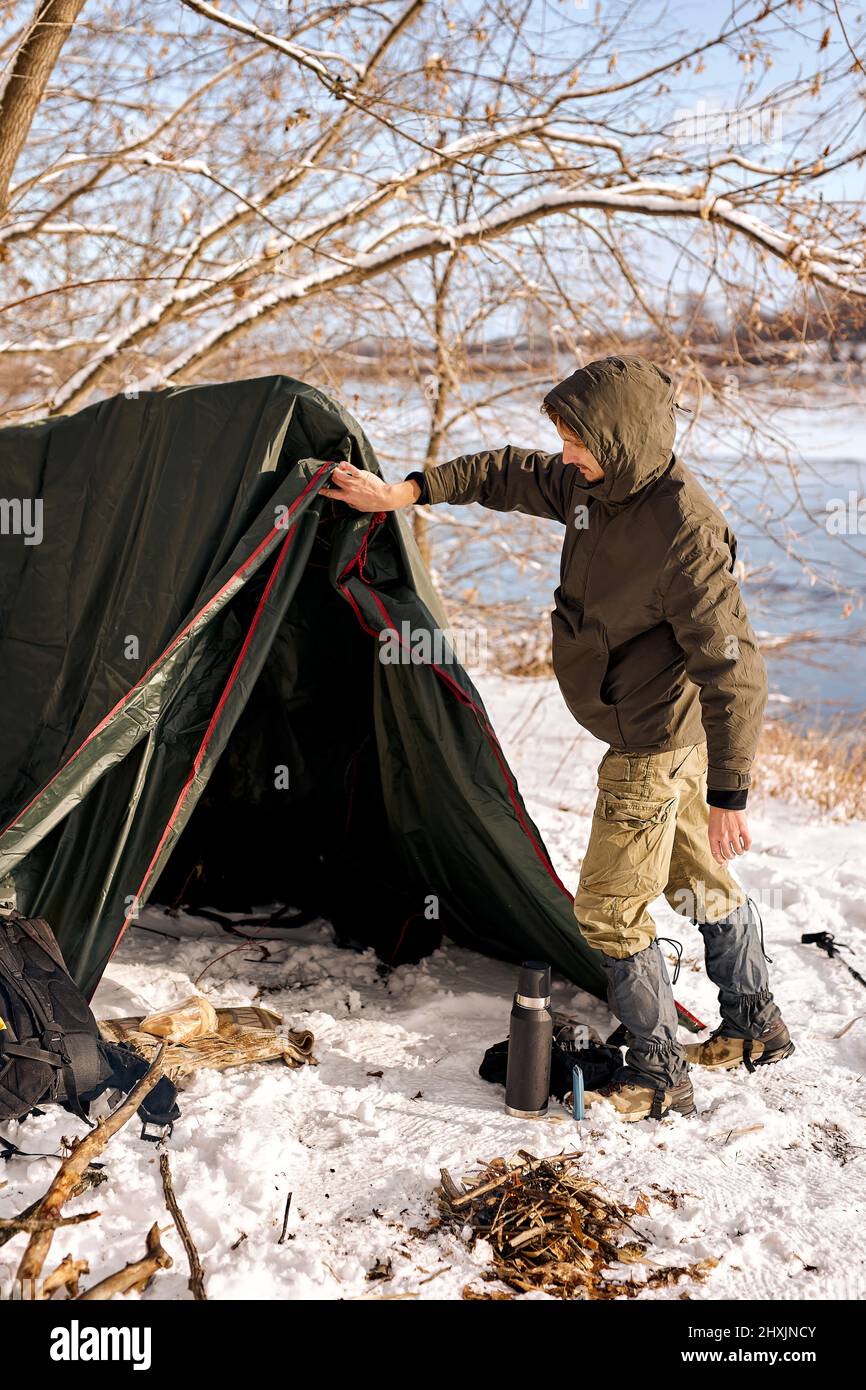 active man hiker setting up tent in forest, pitching in forest clearing ...
