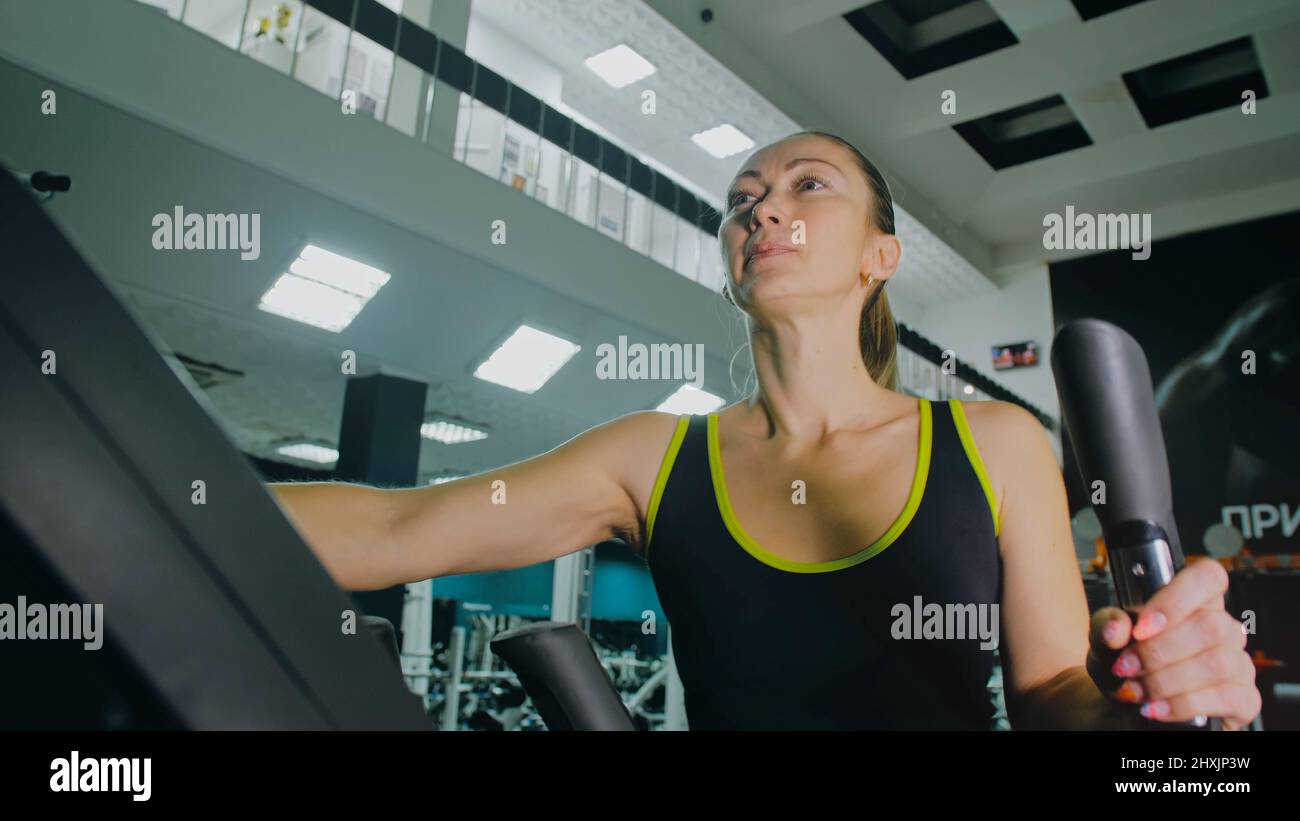 Fit Athletic Woman Exercising on an Elliptical Machine. Muscular Women ...