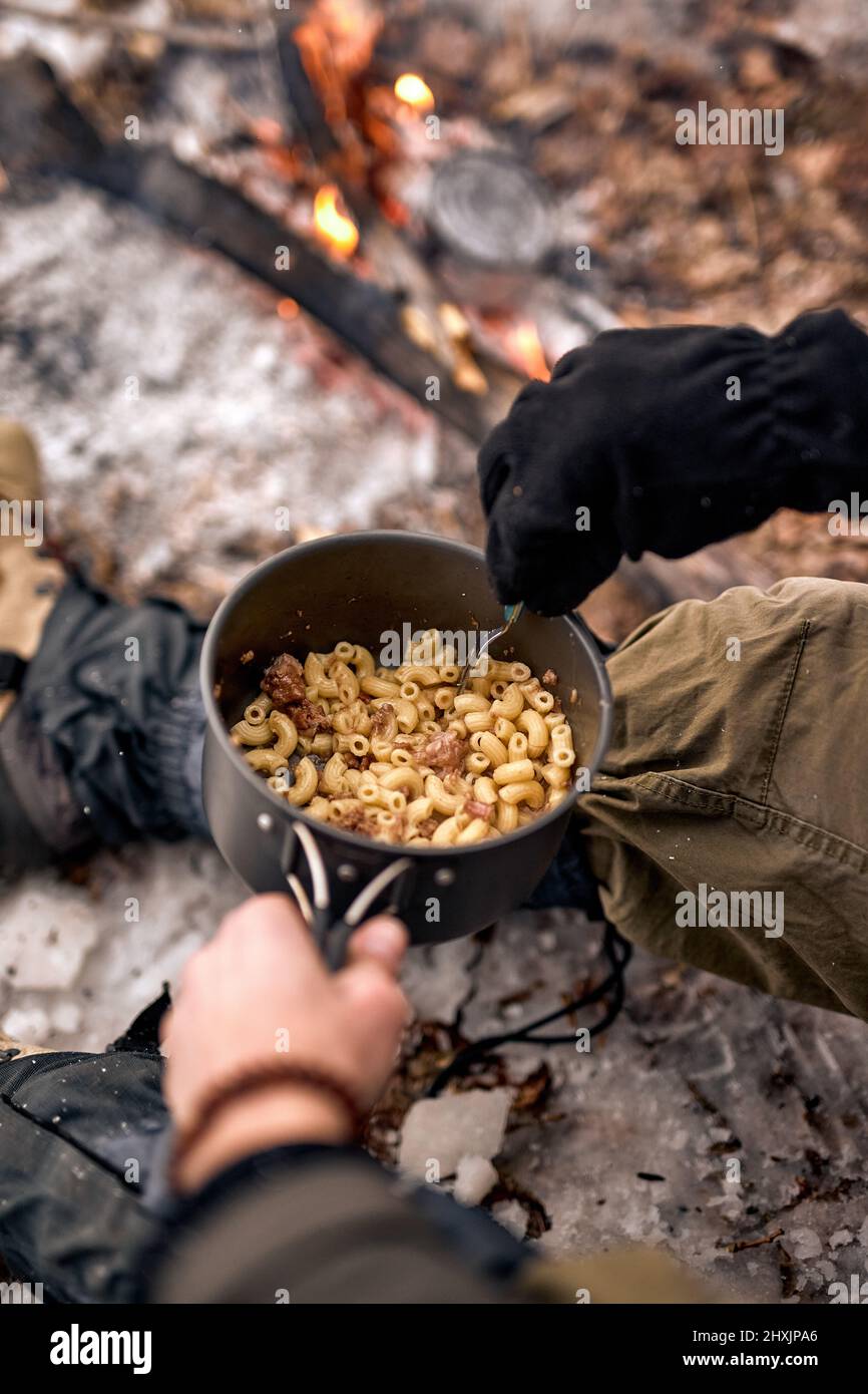 close-up hands of man sitting by campfire alone spending happy holidays ...
