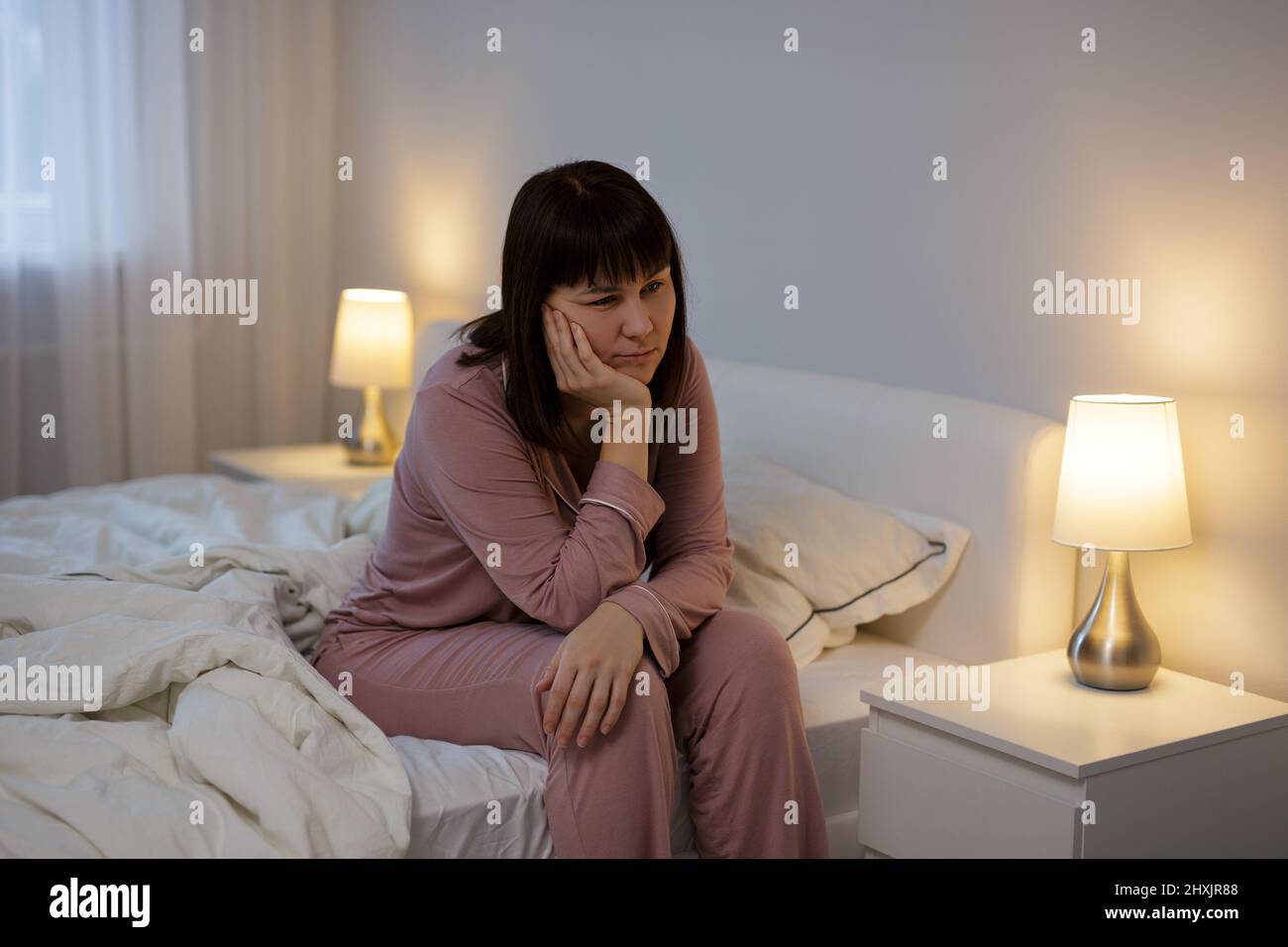 Lonely and sad woman sitting on the bed at home Stock Photo - Alamy