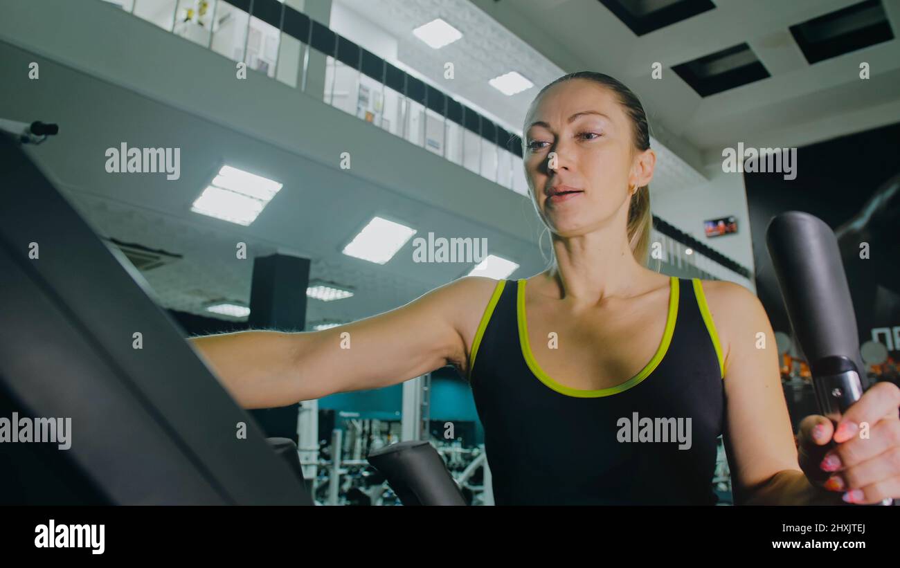 Fit Athletic Woman Exercising on an Elliptical Machine. Muscular Women ...